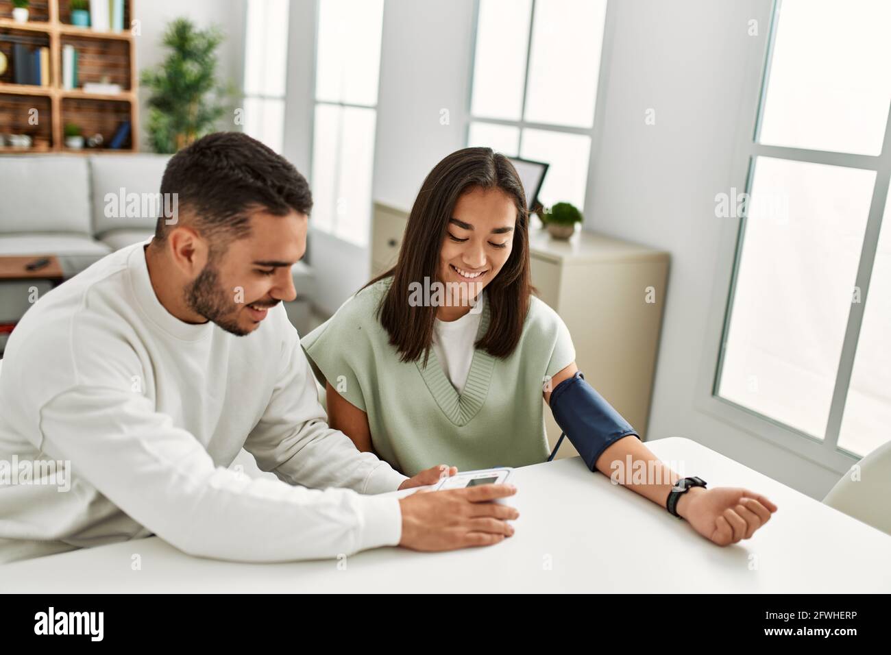 Young latin couple smiling happy measuring blood pressure using ...