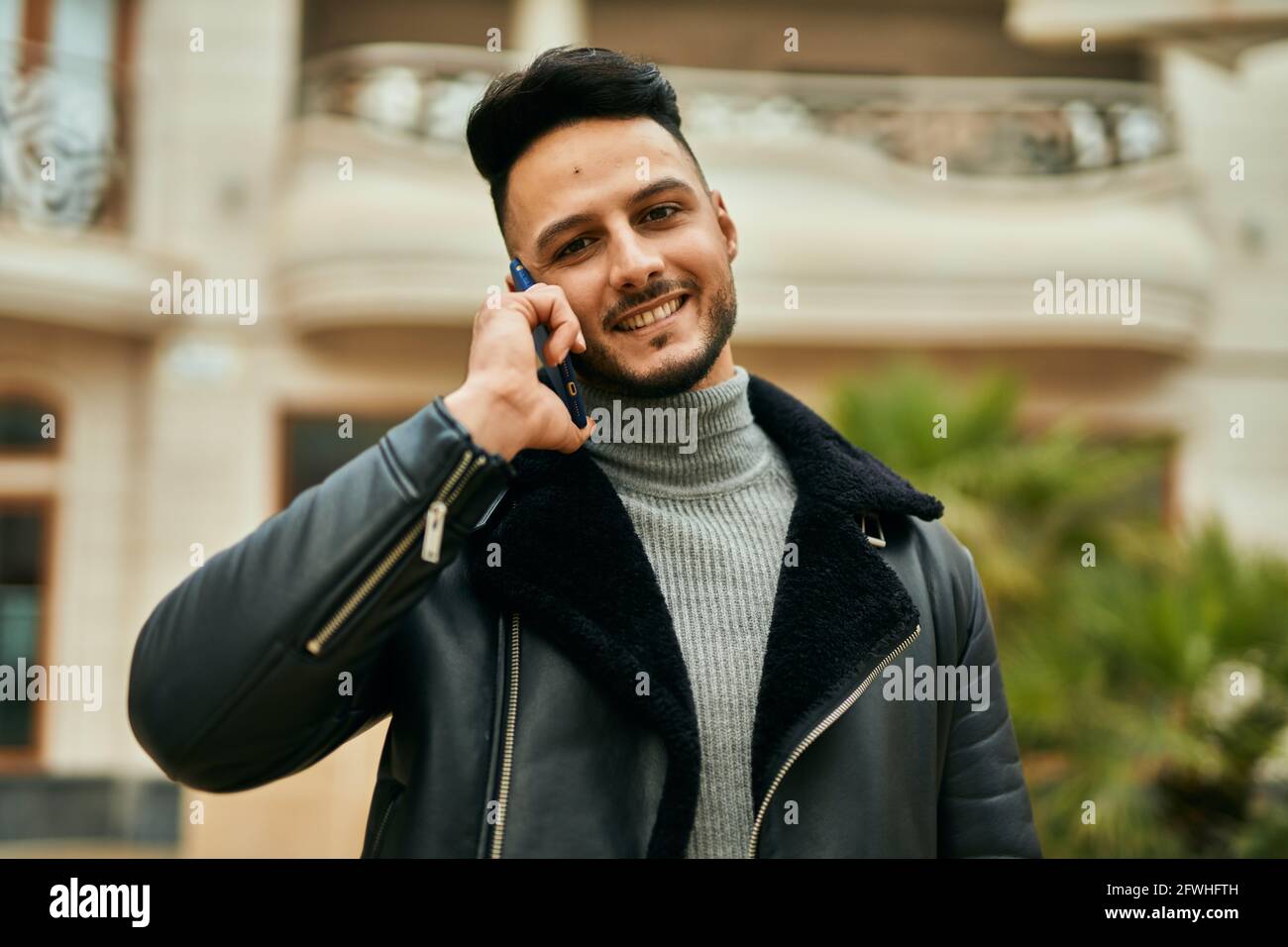 Young arab man smiling happy talking on the smartphone at the city ...