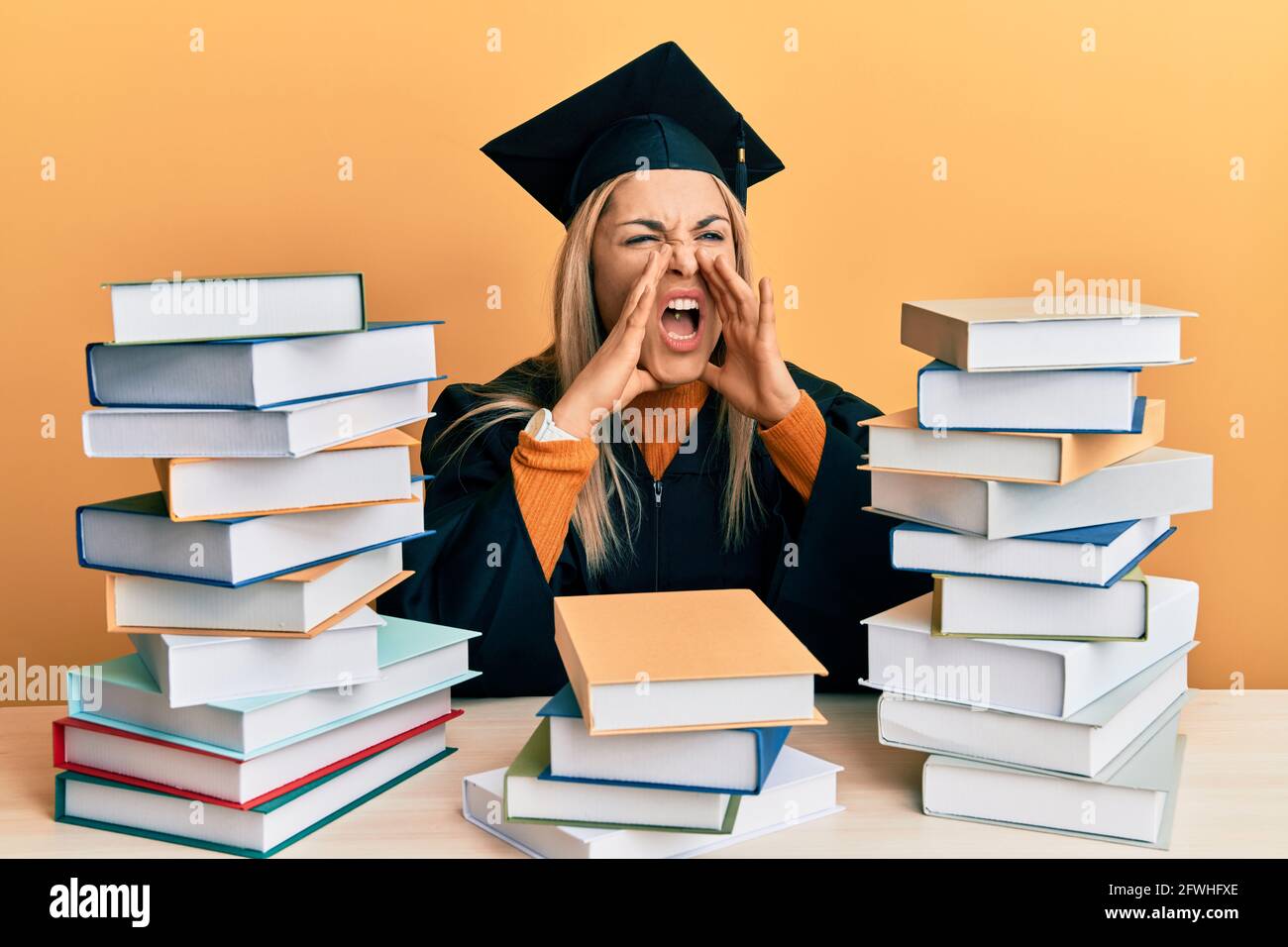 Young caucasian woman wearing graduation ceremony robe sitting on the ...