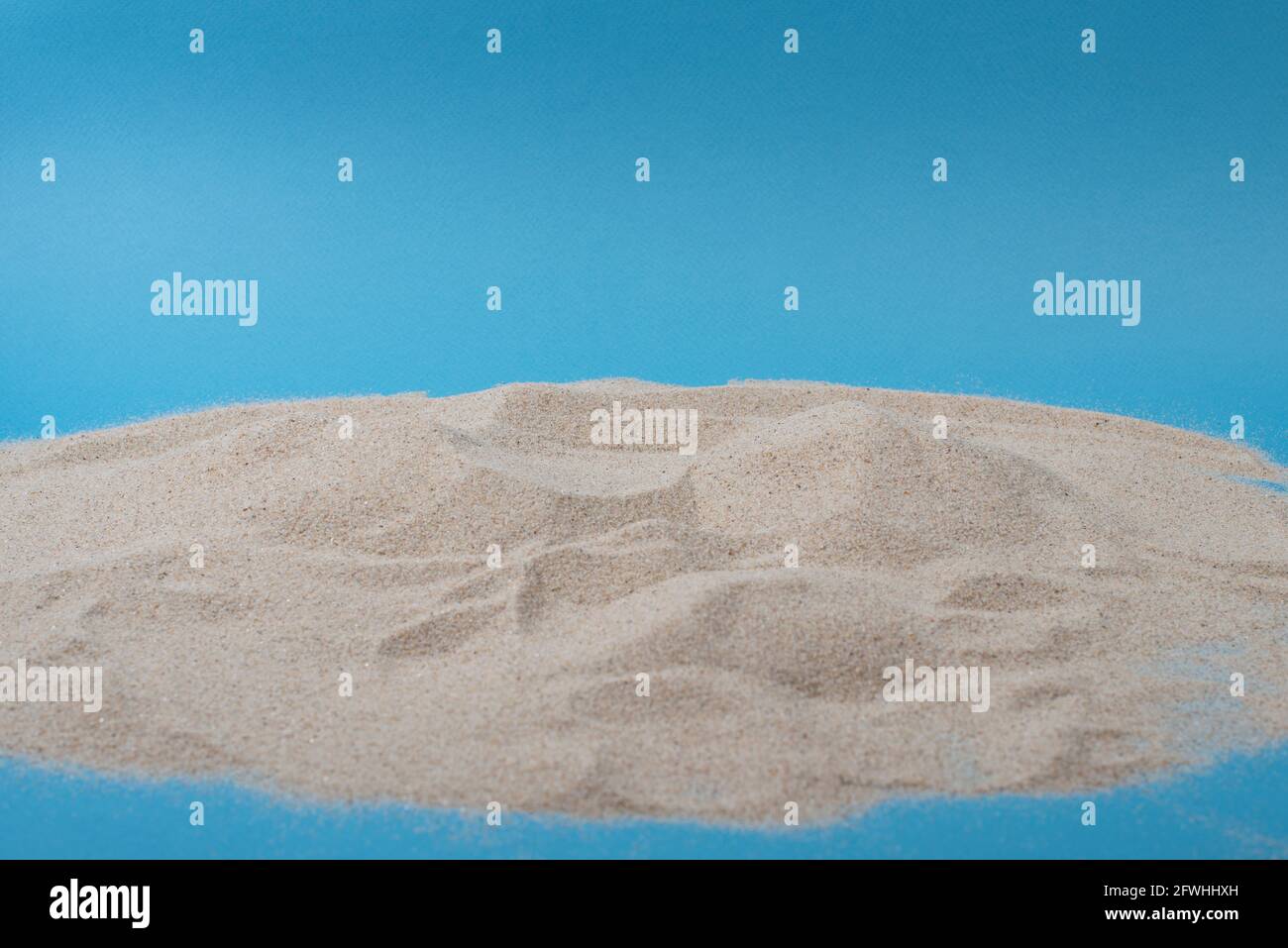Beach sand pile isolated on blue background. Vacation theme Stock Photo ...