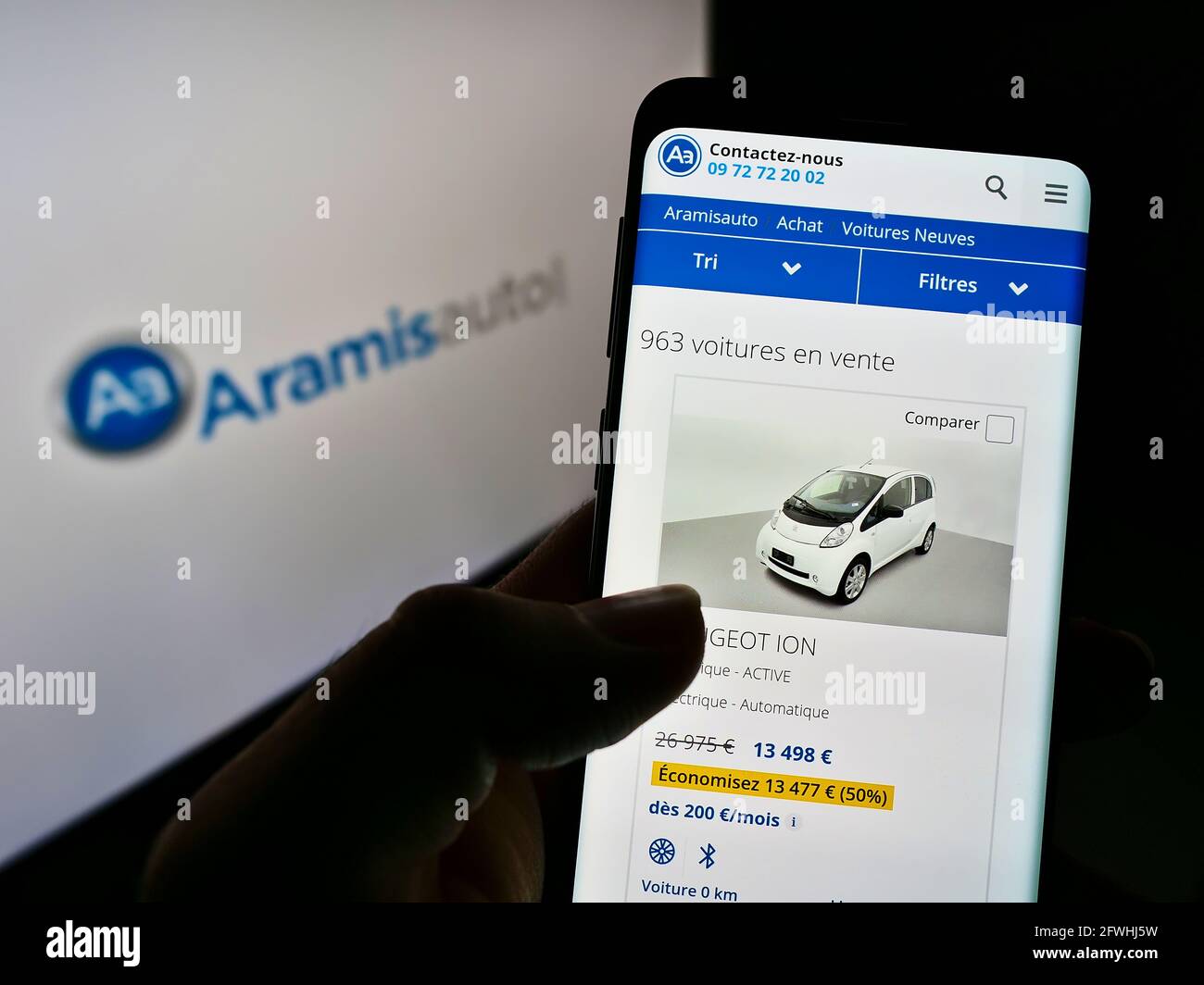 Person holding cellphone with website of French online car dealer ...