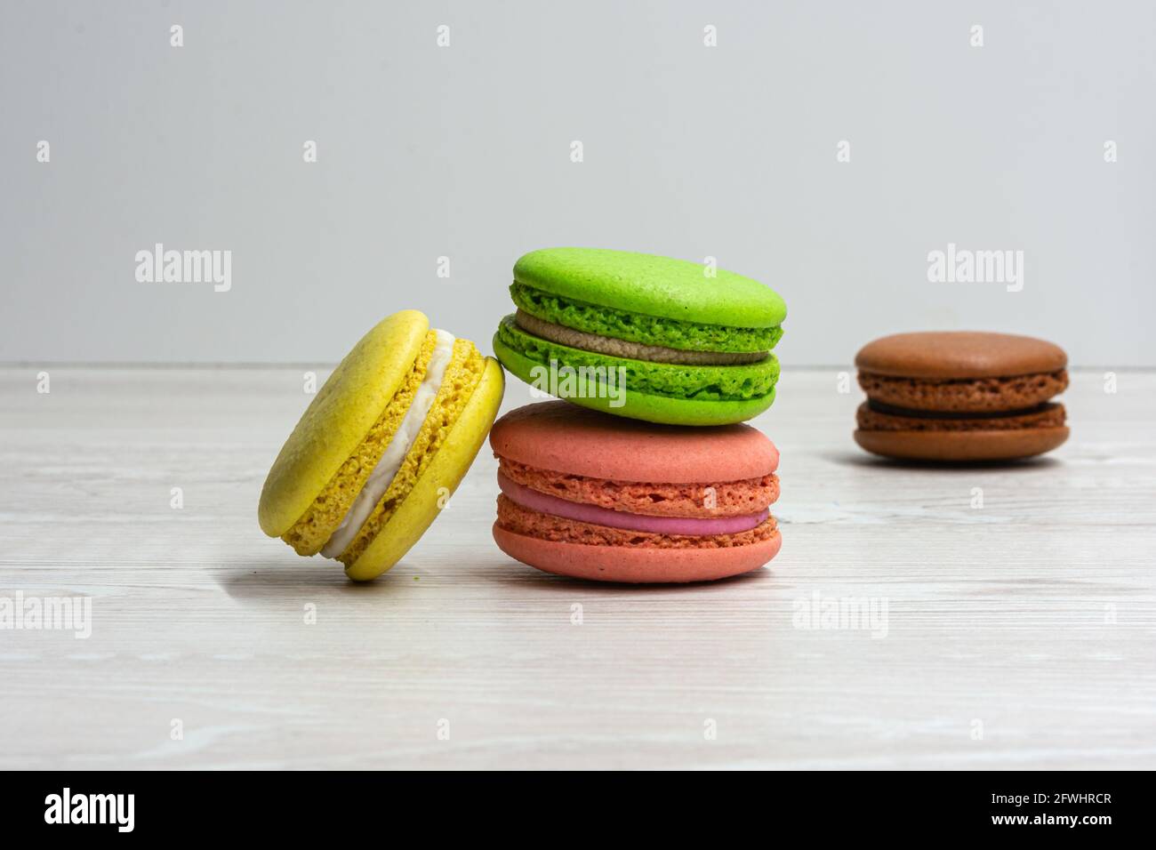 Four multi-colored macaroons on a light kitchen table Stock Photo - Alamy