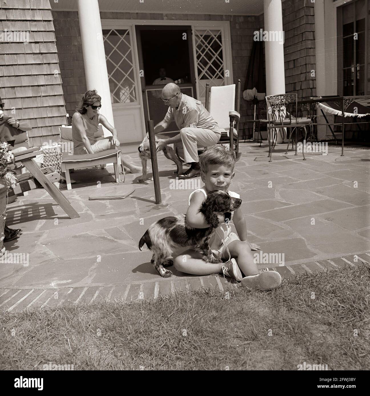 John F. Kennedy, Jr., plays with his dog, Shannon, at Brambletyde house ...