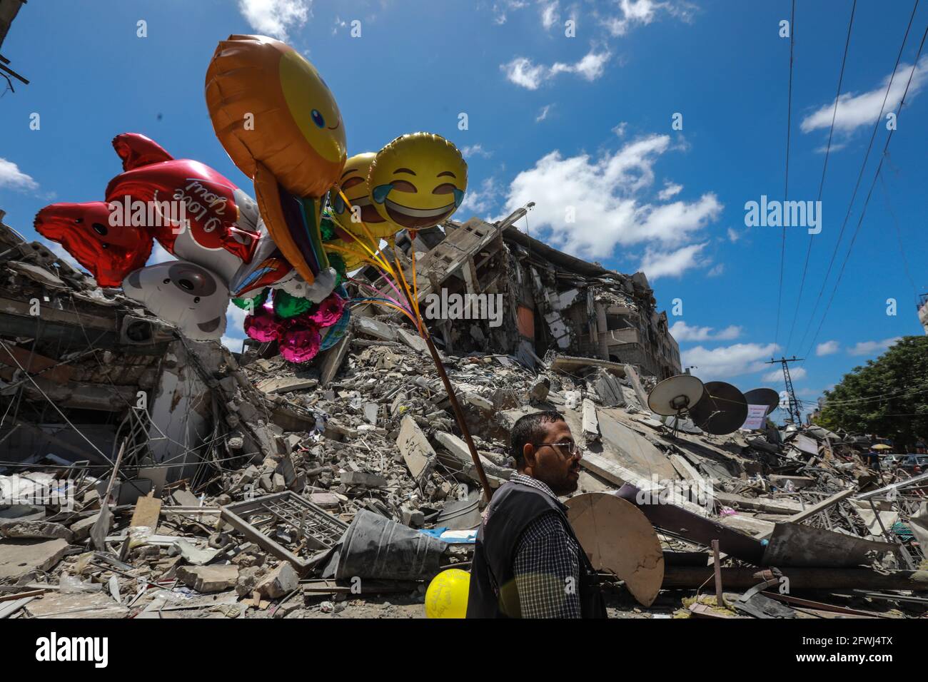 Palestinian man sells balloons near the rubble of Al Shorouq tower ...