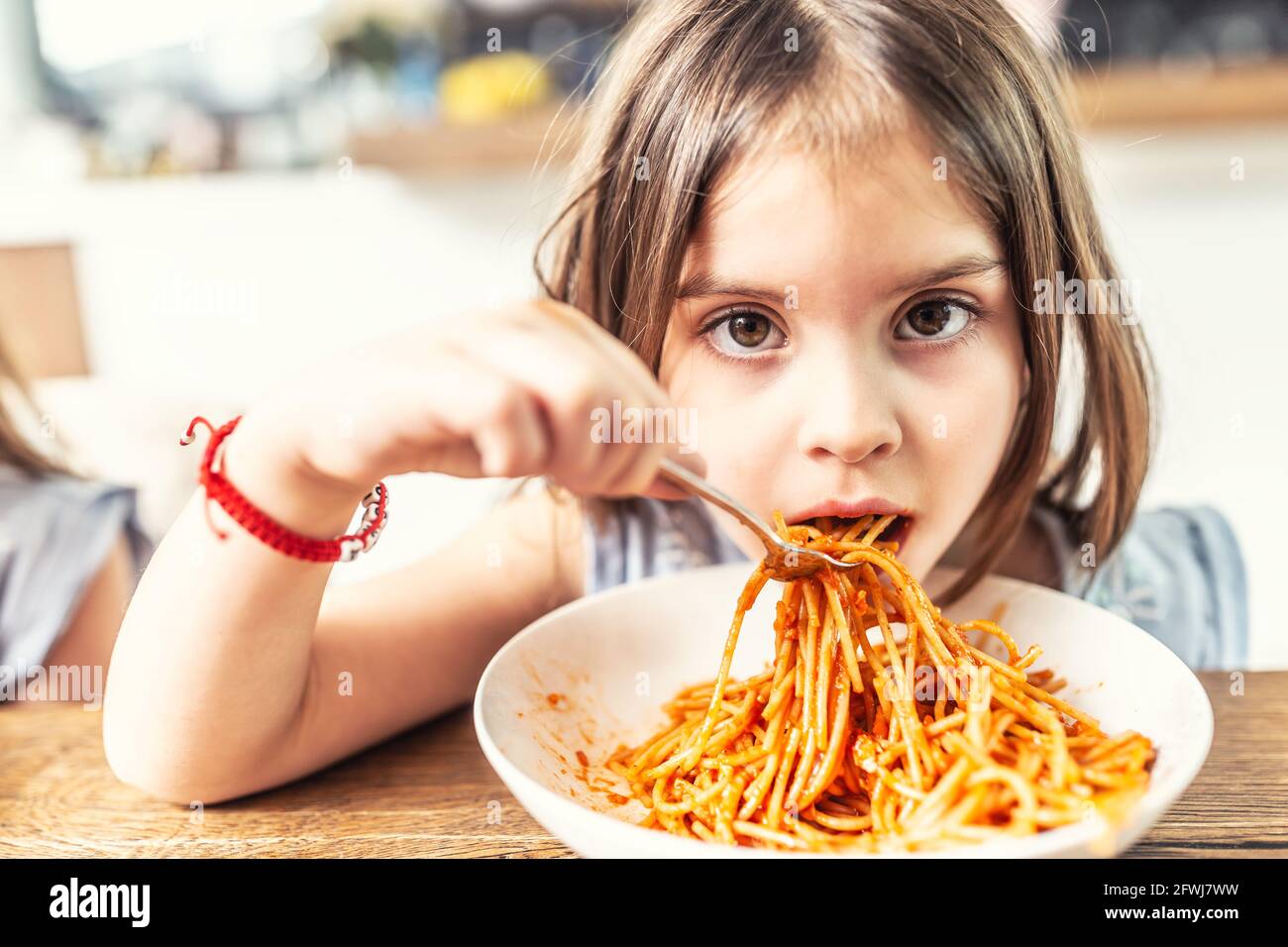 Little girl at home in the kitchen tasting Italian spaghetti Stock ...