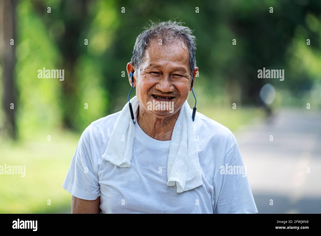 Portrait of asian senior man in fitness wear running in a park. Close ...