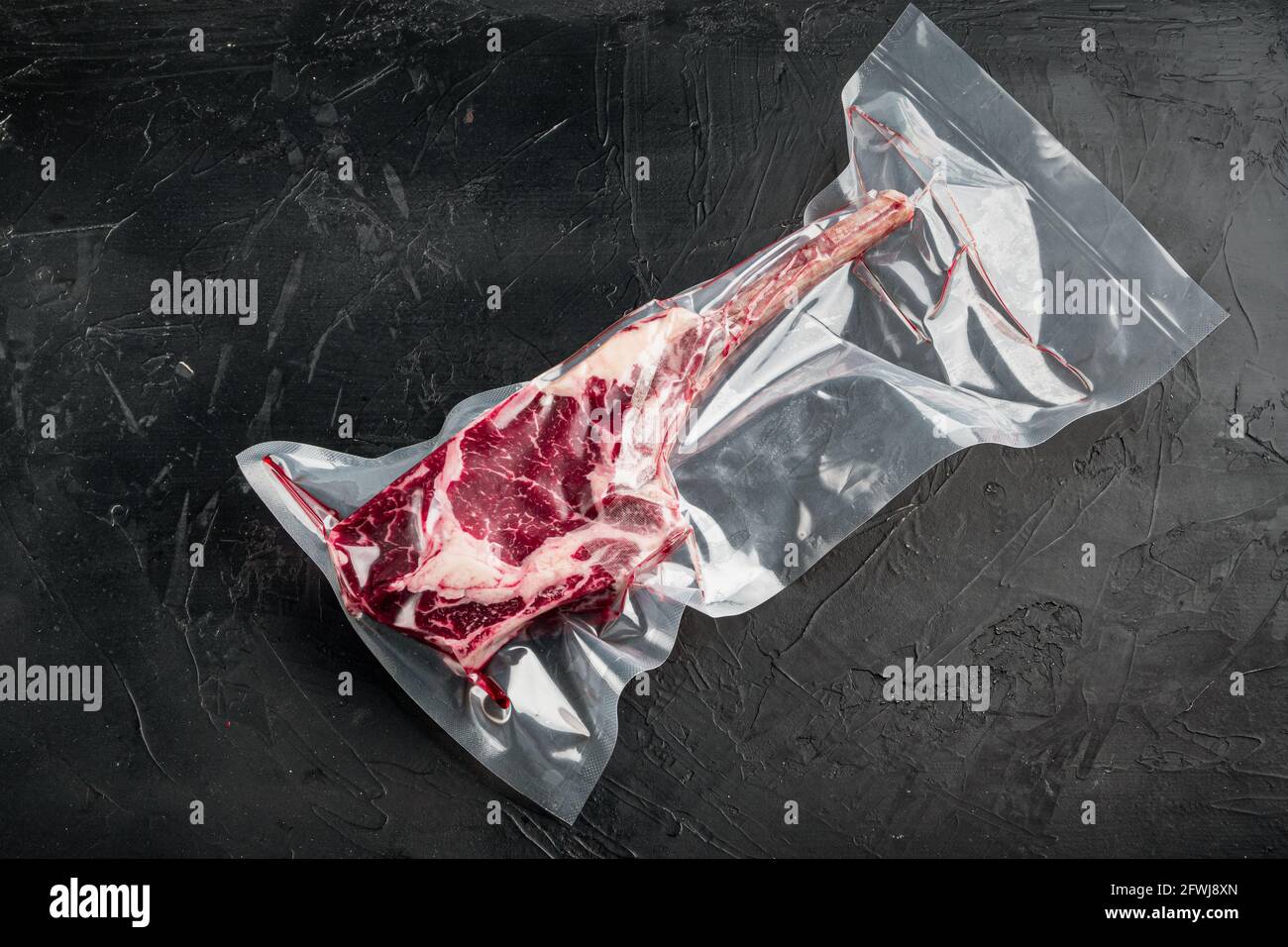 Fresh tasty raw beef Tomahawk steak with bone wrapped in vacuum plastic ...