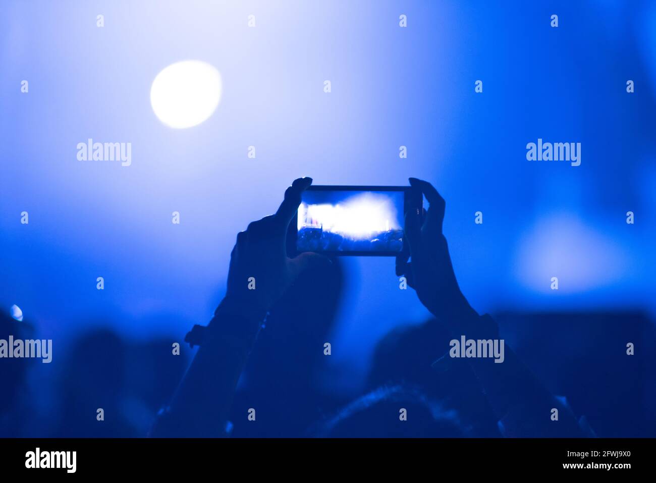 Hand holding smart phone and recording photo or video. Concert crowd ...