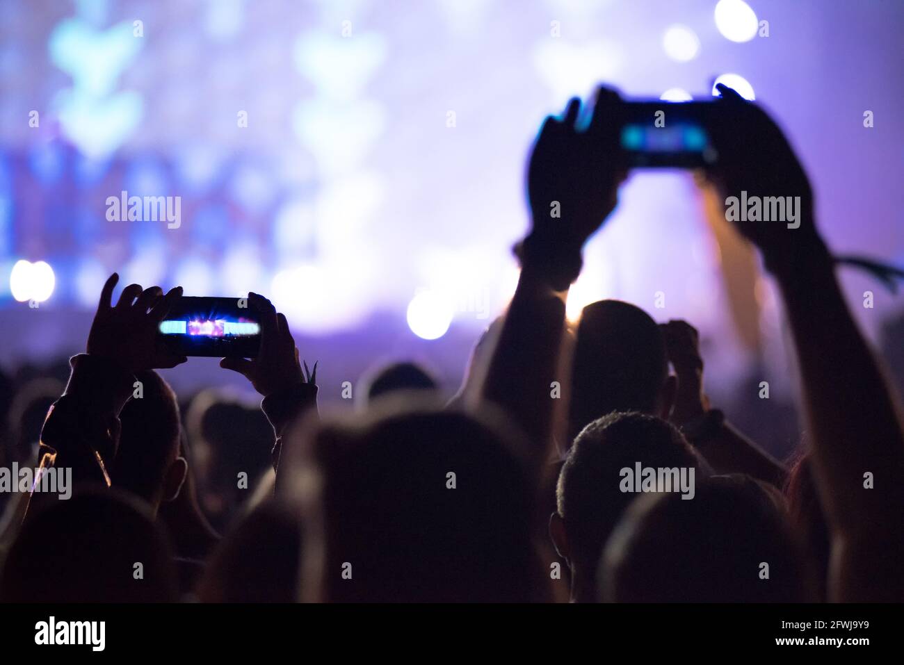 Hand holding smart phone and recording photo or video. Concert crowd ...