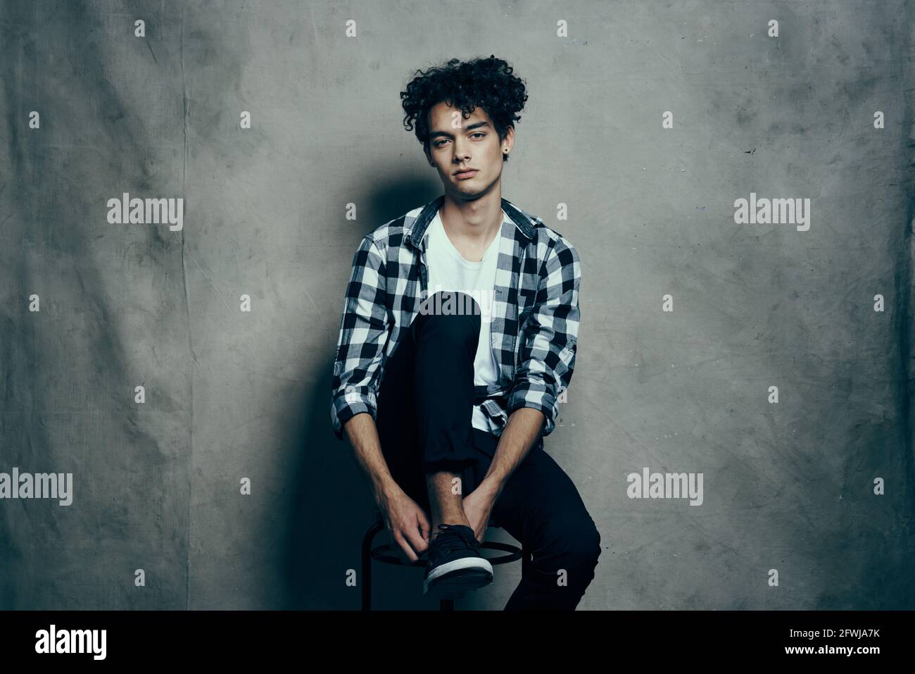 guy sitting on a chair curly hair plaid shirt fashion lifestyle Stock Photo - Alamy