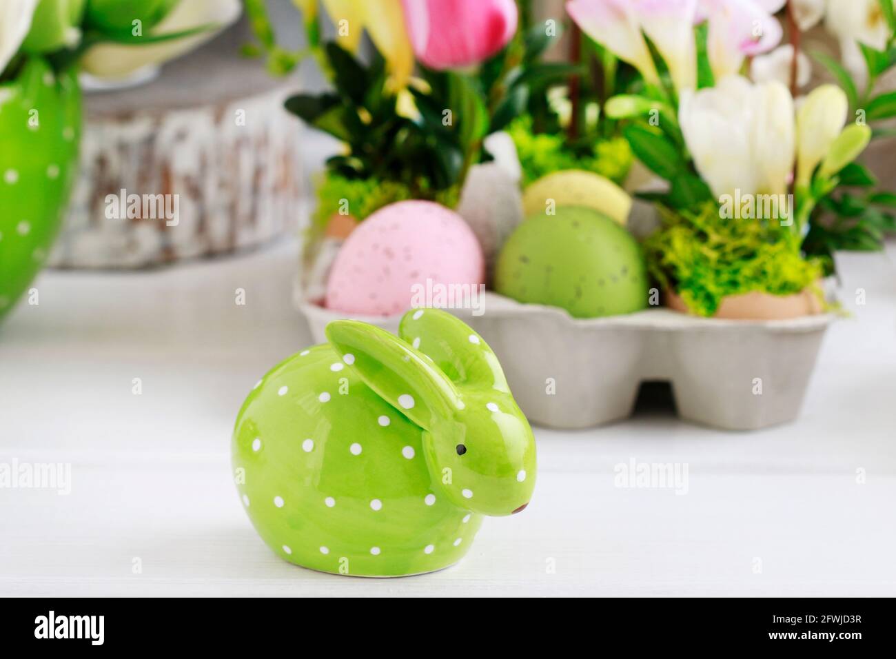 Dotted green ceramic rabbit and floral decoration in the background ...