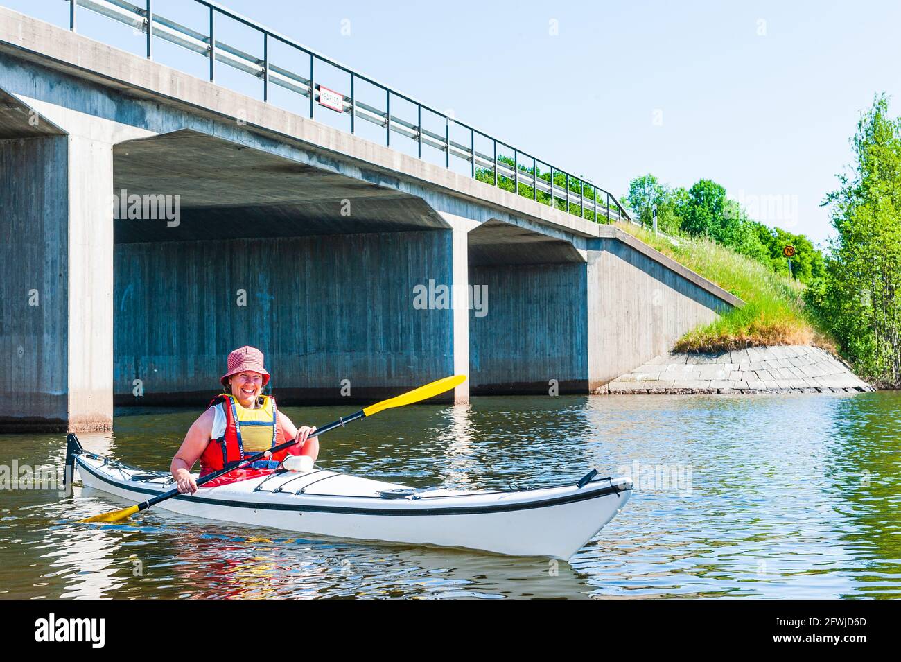 Woman kayaking in front of road bridge Stock Photo - Alamy