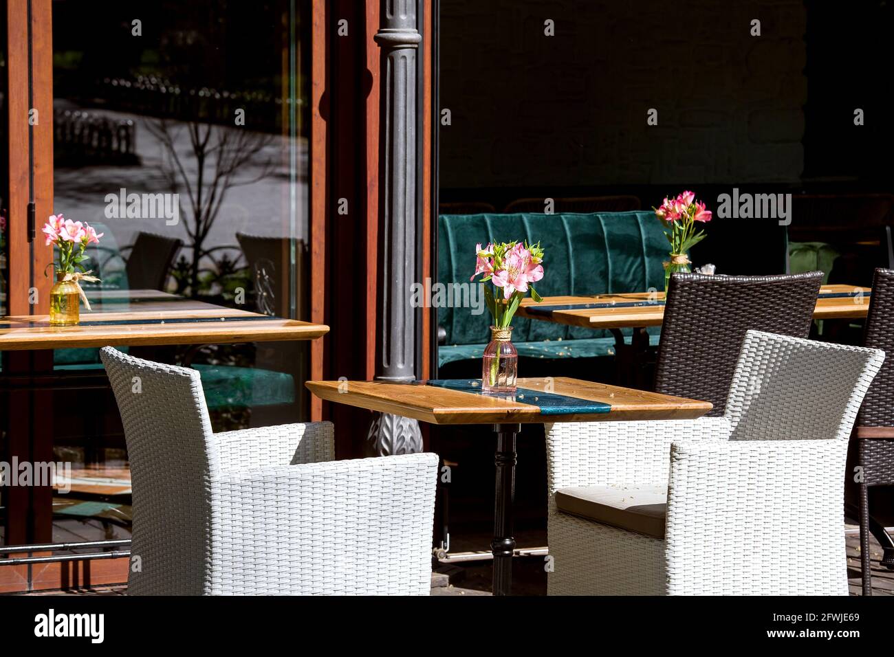 outdoor cafe terrace with wooden tables with a glass vase and a flower ...