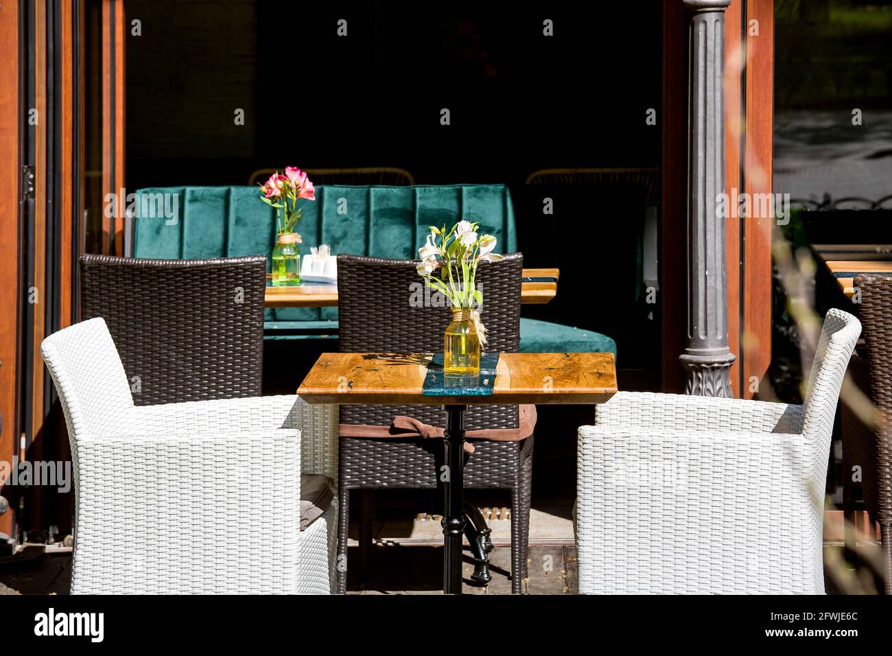 outdoor cafe terrace with wooden tables with a glass vase and a flower ...