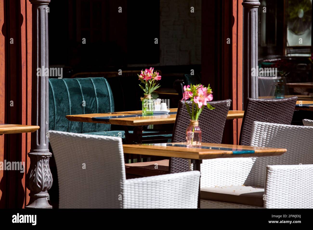 outdoor cafe terrace with wooden tables with a glass vase and a flower ...