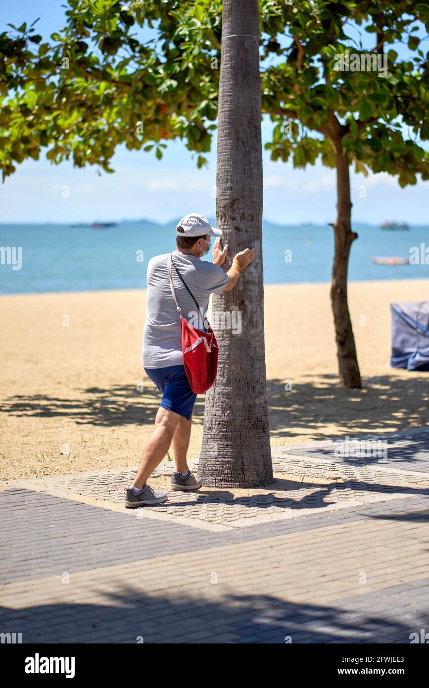 Limbering up. Man pushing against tree and limbering up as part of his ...