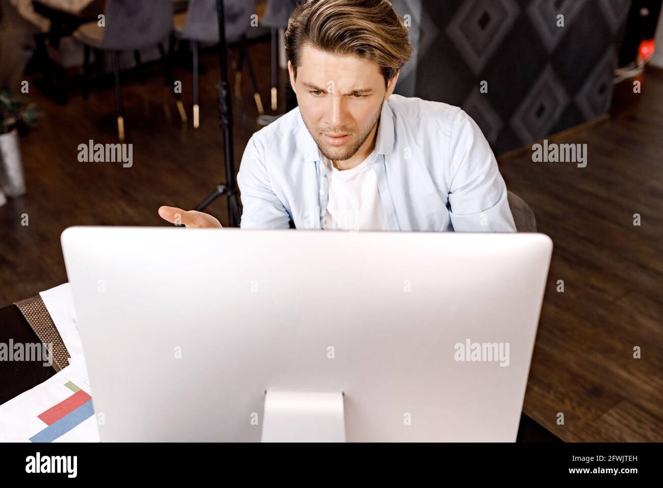 Confused young Caucasian male worker freelancer look at computer screen ...