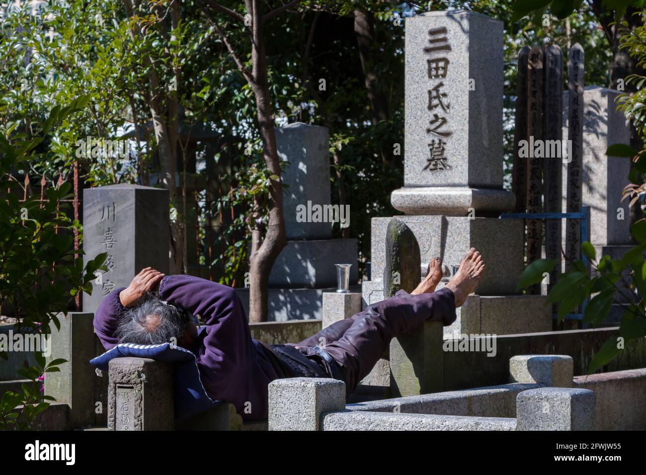 A homeless man sleeps on gravestones in a cemetery in Azabu. (Photo by ...