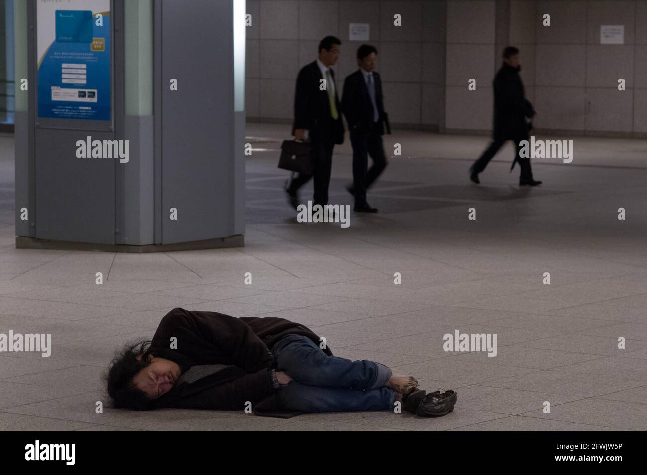 Salarymen or office workers walk past a Japanese homeless man sleeping ...