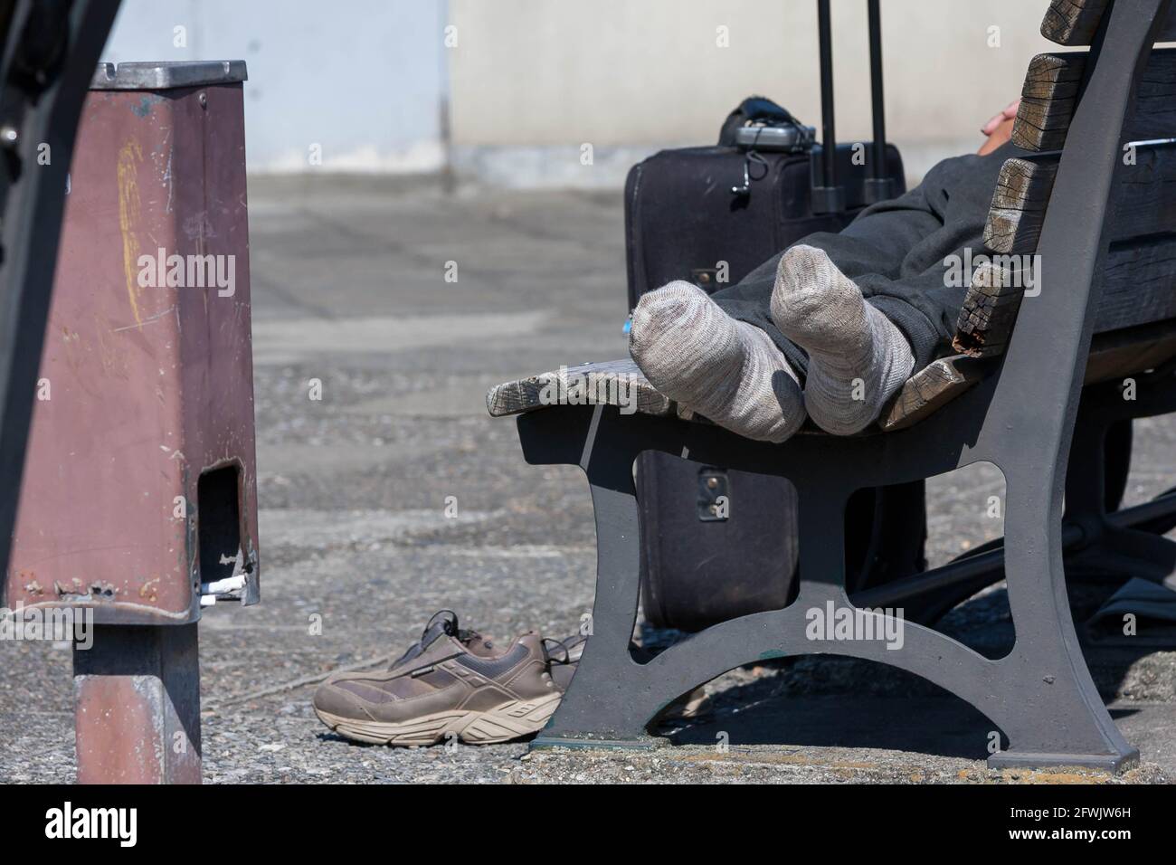 The feet of a homeless man sleeping on a park bench in Ueno Park ...