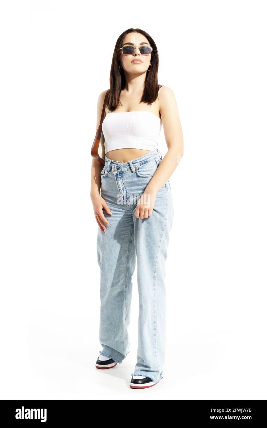 Relaxed young gen Z woman in sunny summer day looking up holding jeans ...