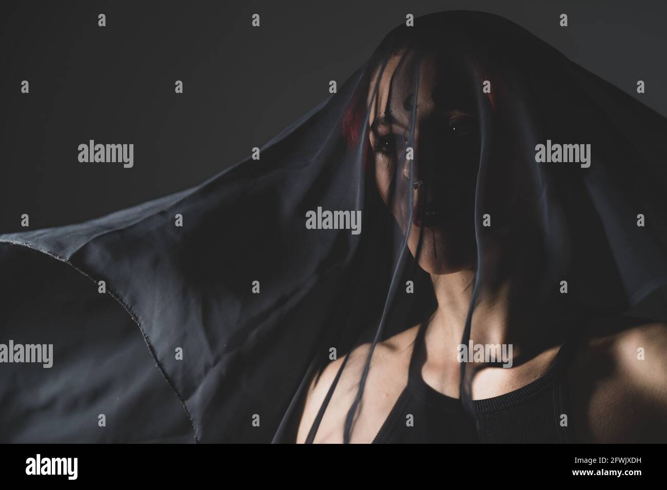 Woman in a black veil with dark makeup and an earring in her nose ...