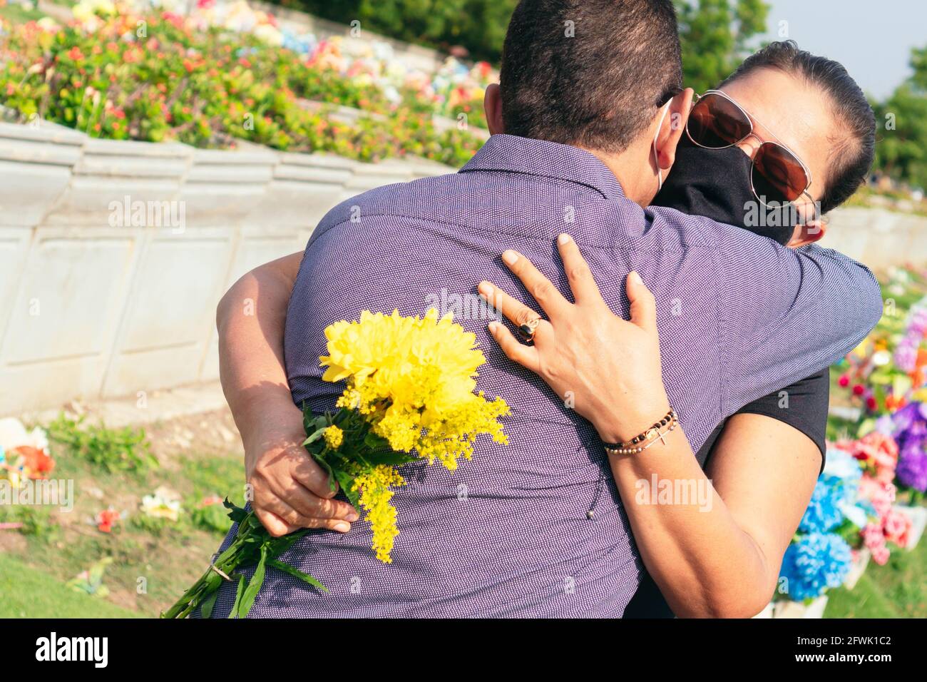 Couple with protective mourning mask holding flowers in hands and ...