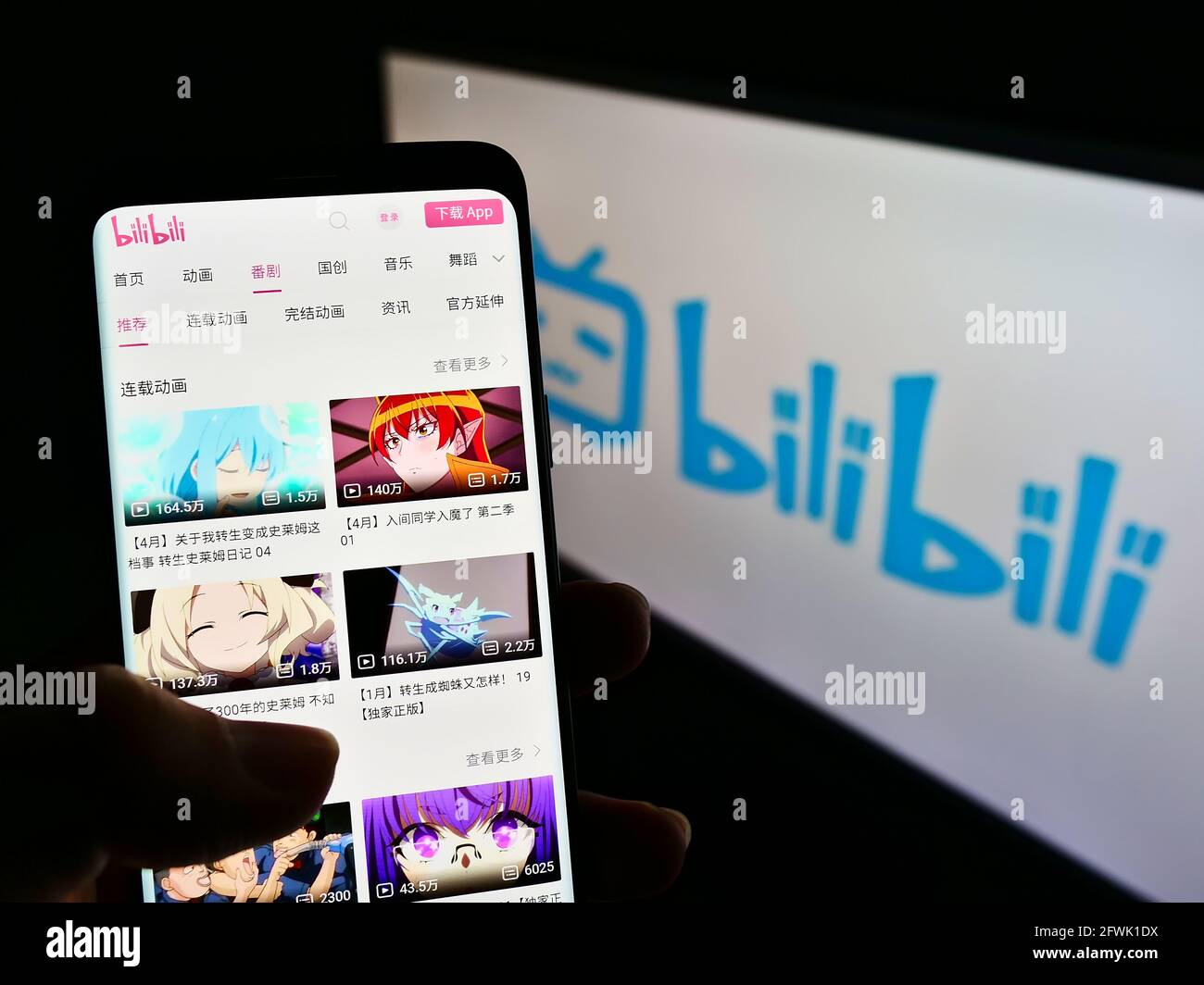 Person holding cellphone with website of Chinese video sharing platform ...