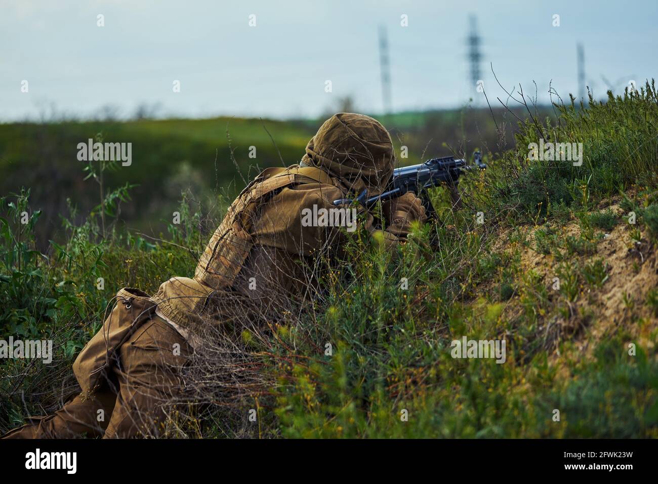 Close-up of a soldier lying on the ground and aiming at the scope of ...