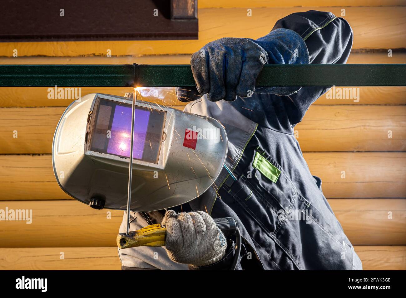 Worker male welder at a construction site welds a metal structure on a ...