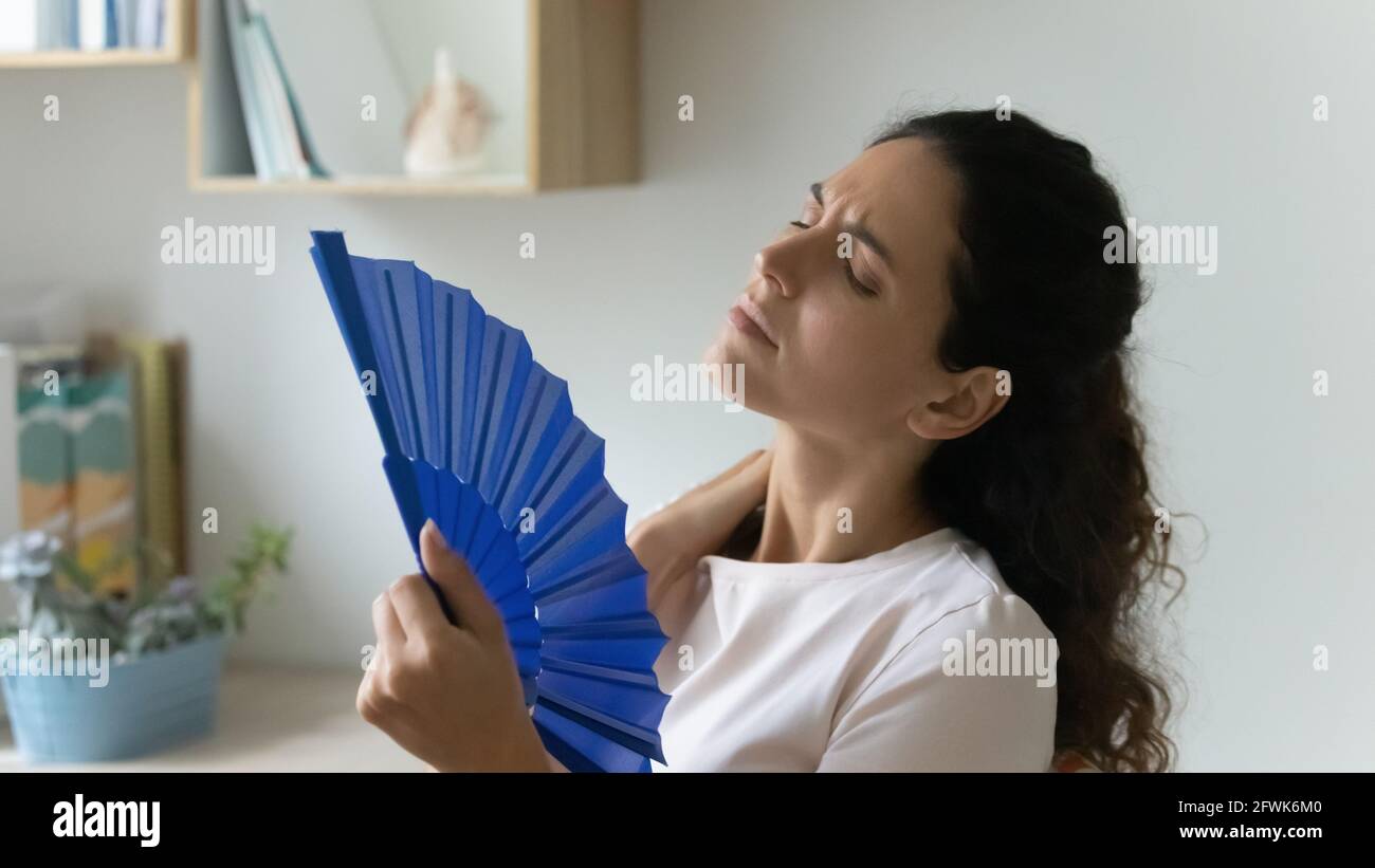 Overheated stressed millennial woman waving paper fan Stock Photo - Alamy