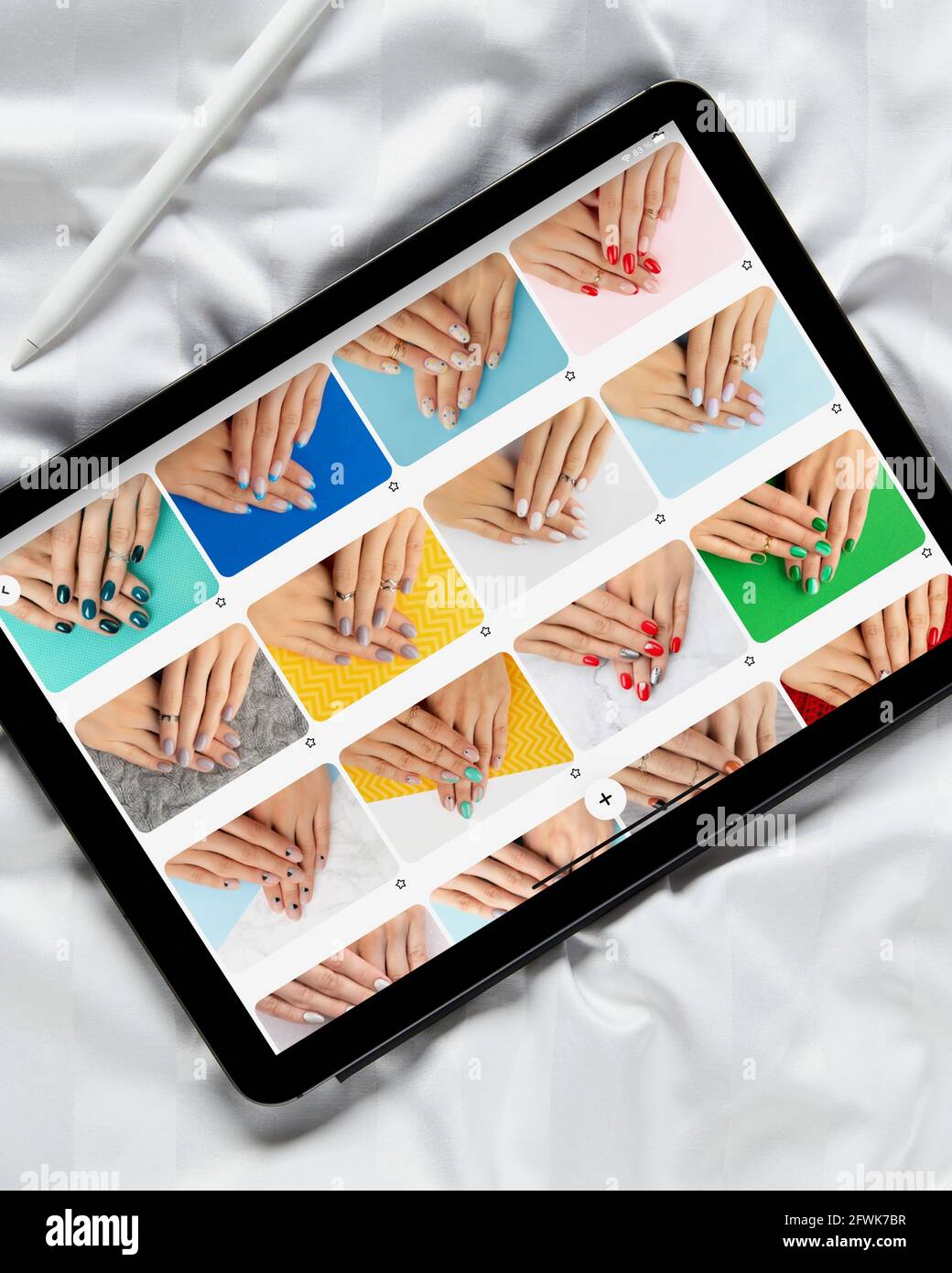 Black tablet with manicure designs on screen on white bed. Beauty salon ...