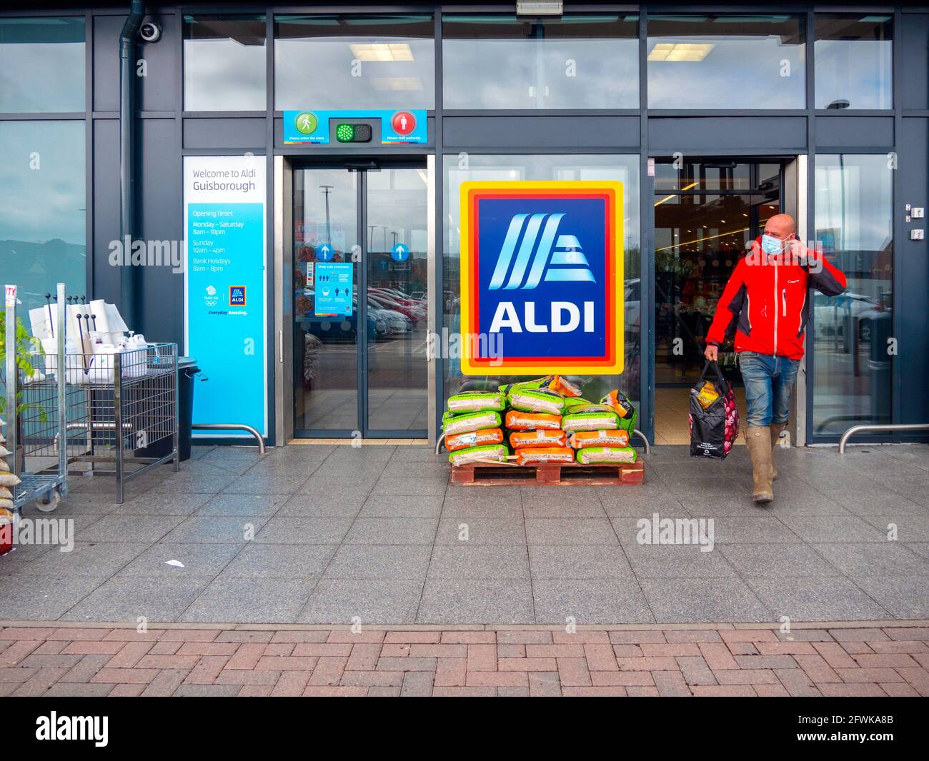 A man exiting an Aldi supermarket in Gusborough wearing a red jacket ...