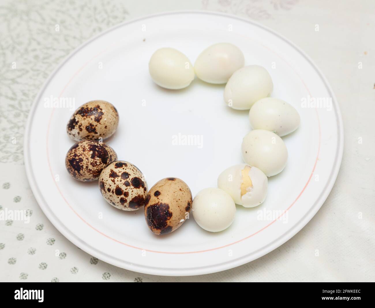 A plate with boiled quail eggs, some with the shell and some without ...
