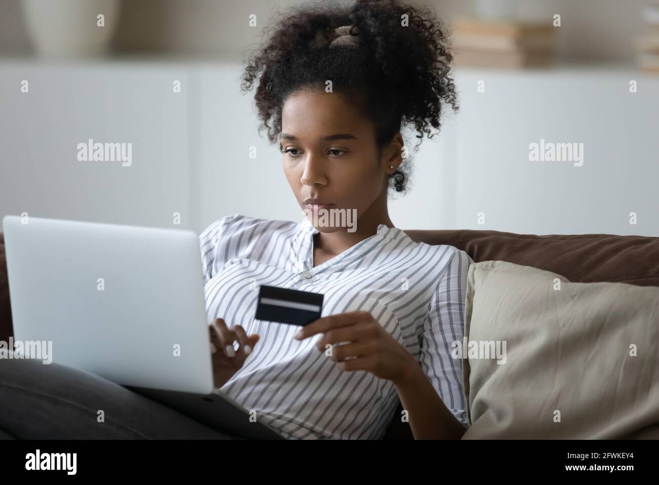 Concentrated young african woman entering payment information in ...