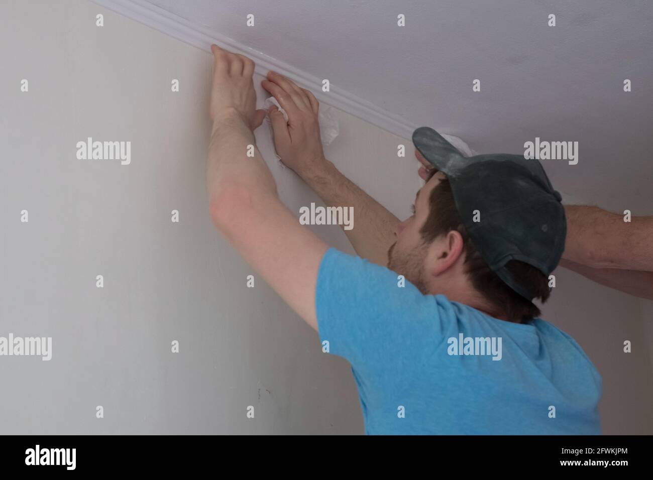 Man putting white ceiling skirting on ceiling Stock Photo - Alamy