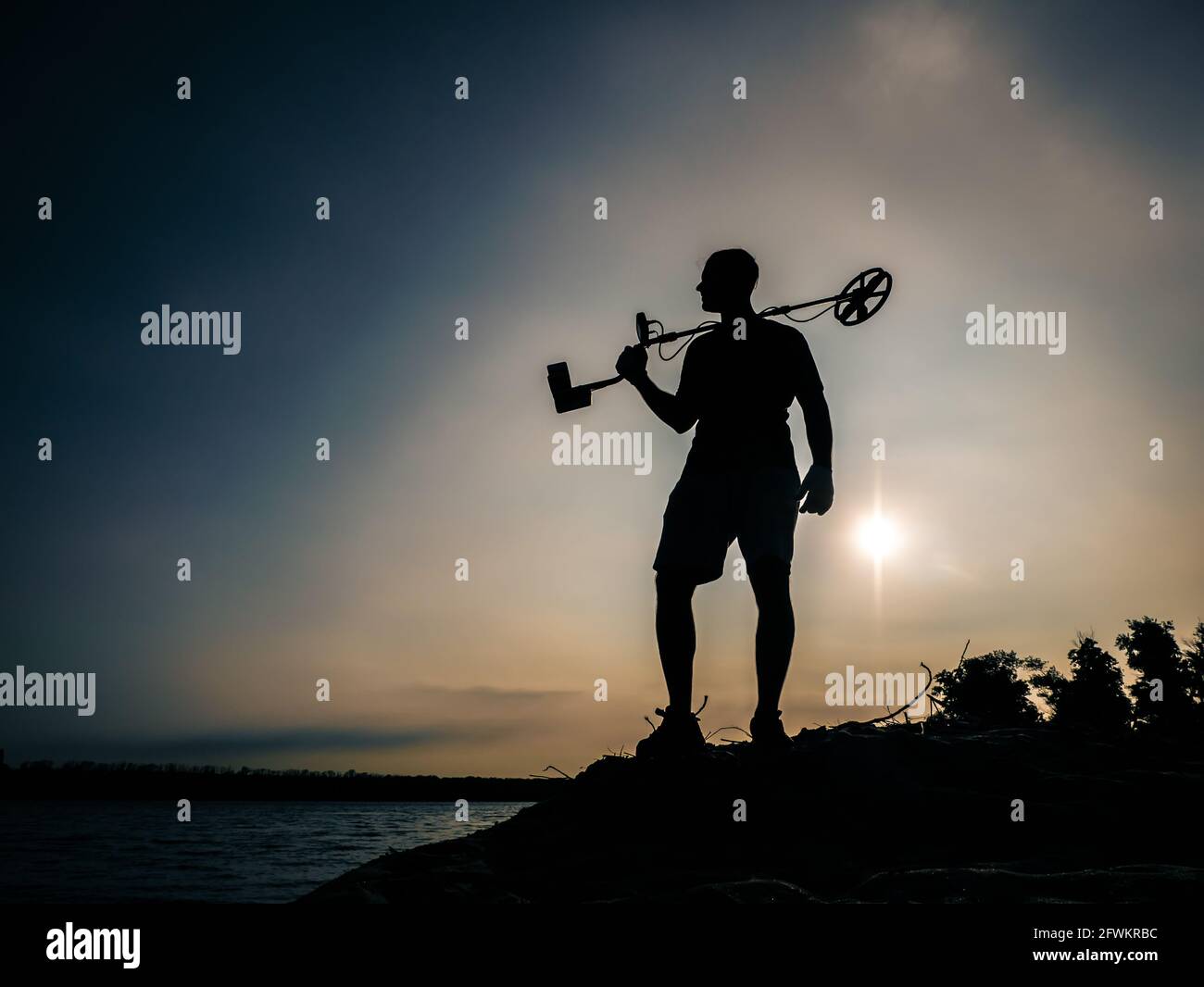 Guy with a metal detector stands against the backdrop of a beautiful ...