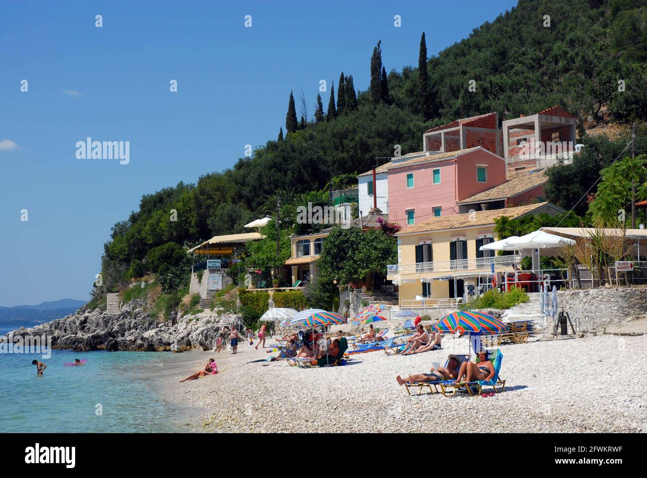 People sunbathing on a shingle beach, east Corfu, Greece Stock Photo ...
