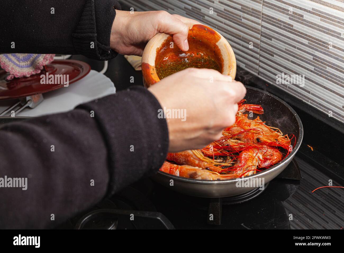 Cooking grilled shrimp in a skillet on a gas stove in the kitchen. The ...