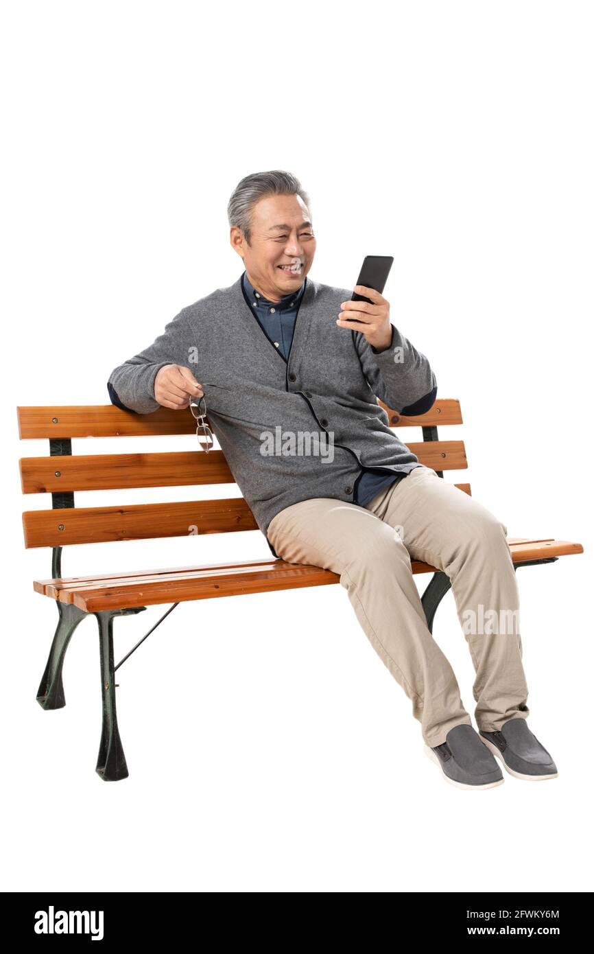 Happy old man sitting on a bench watching mobile phone Stock Photo - Alamy