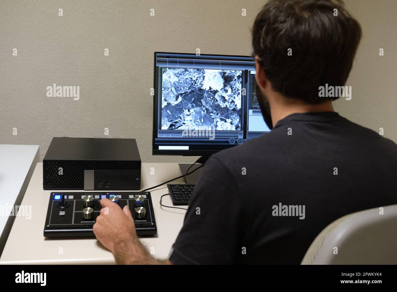 Young man scientist working with scanning electron microscope ...
