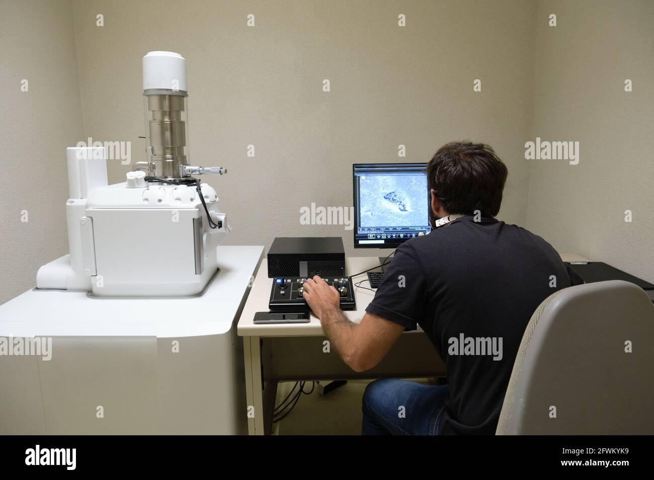 Young man scientist working with scanning electron microscope ...
