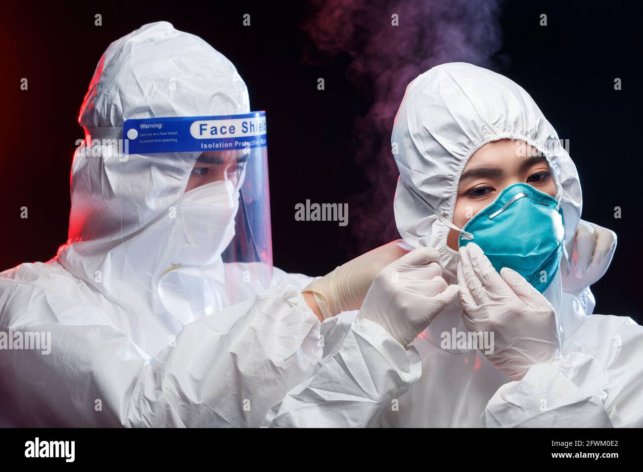 Wear protective clothing of young men to help colleagues to adjust mask ...