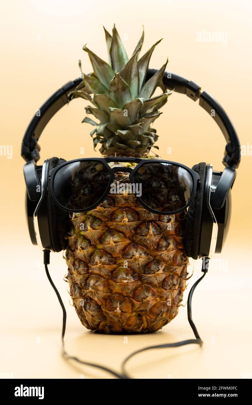 Closeup of cool pineapple in sunglasses wearing headphones looking at ...