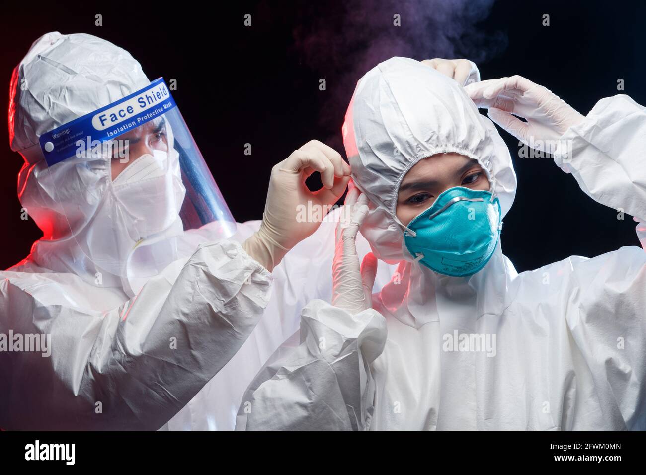 Wear protective clothing of young men to help colleagues to adjust mask ...