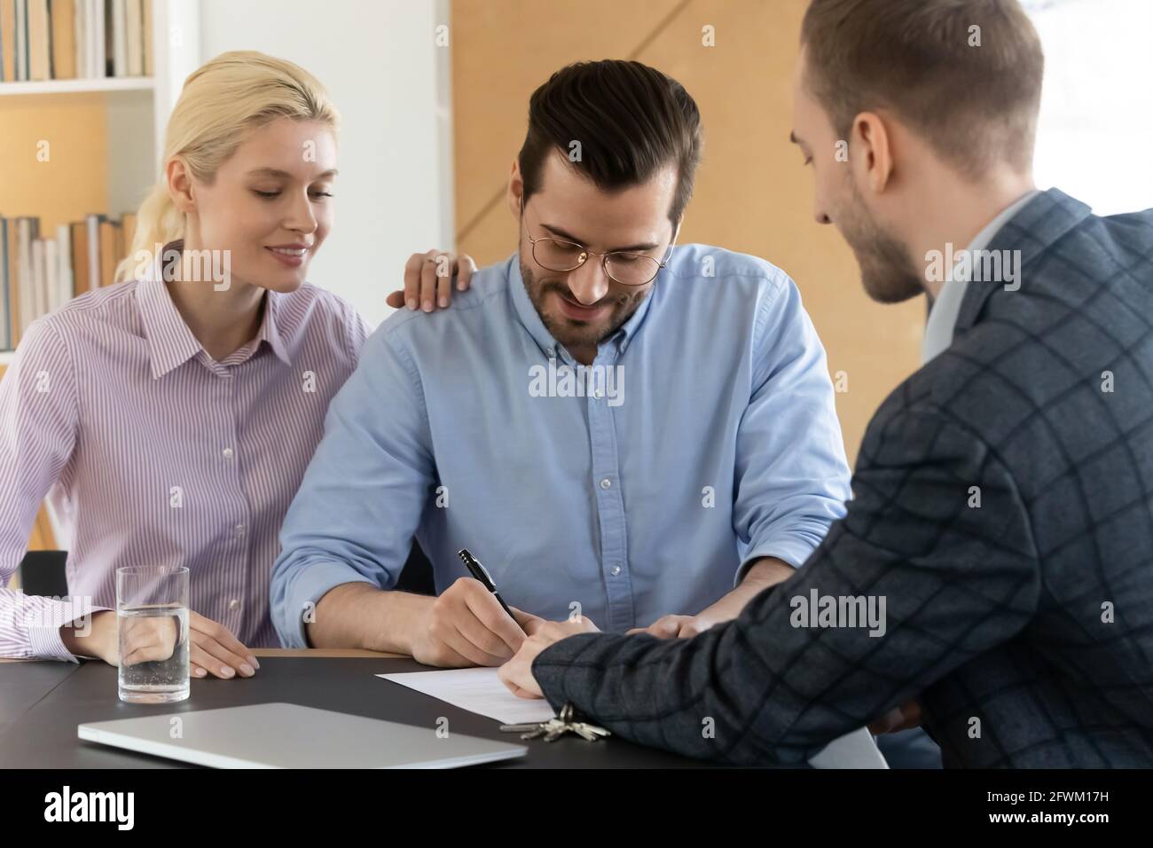 Happy millennial couple signing contract, making deal at meeting Stock ...