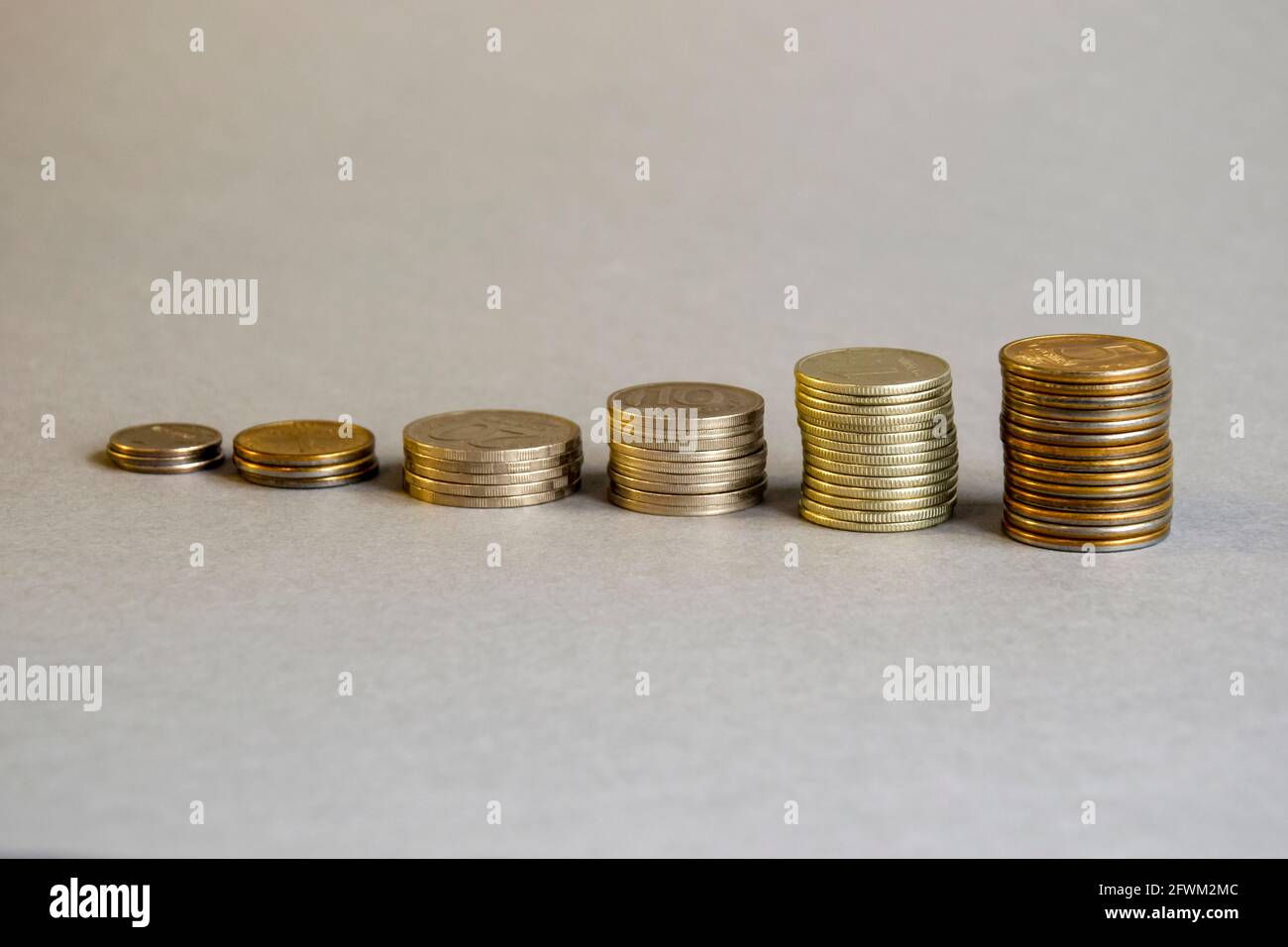 Coins of different sizes and denominations stacked in ascending piles ...