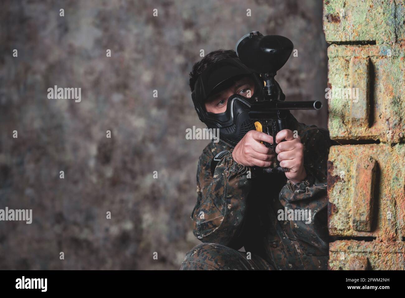 Young man playing paintball battle game with his friends, wearing ...
