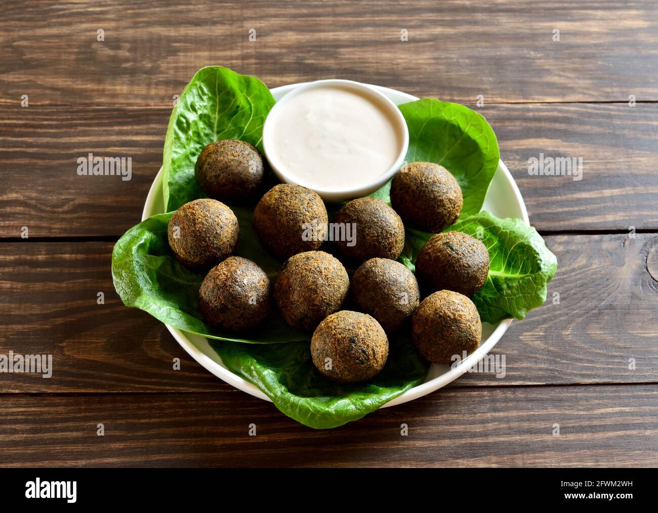 Close up view of falafel balls with sauce on wooden background. Deep ...
