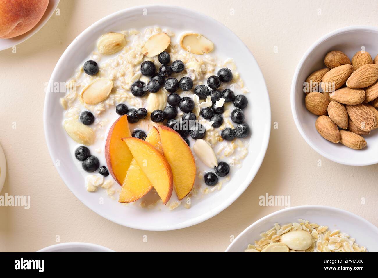 Oatmeal porridge with peach slices, almond and wild blueberries in bowl ...
